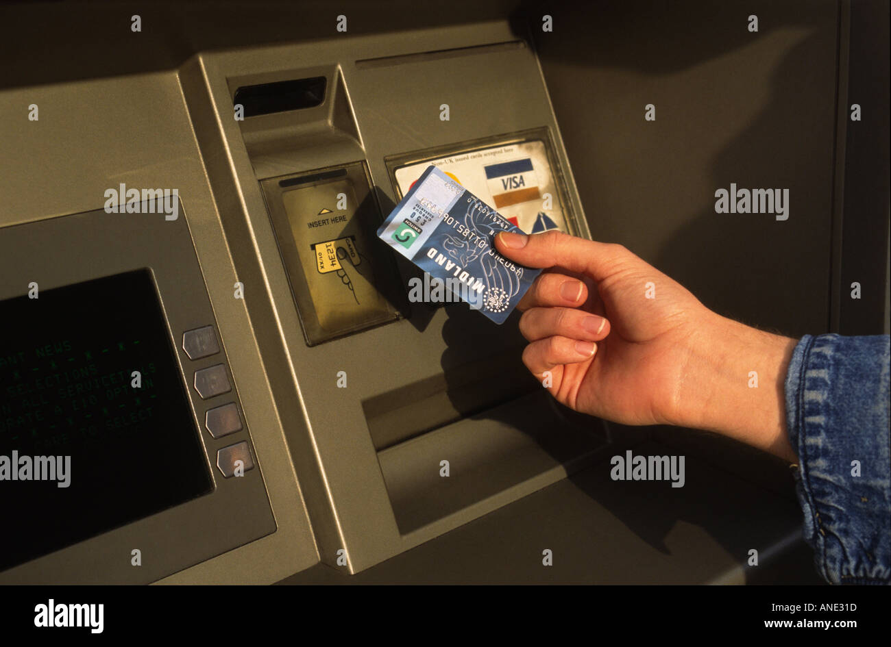 Mans hand putting card into an ATM machine Stock Photo - Alamy