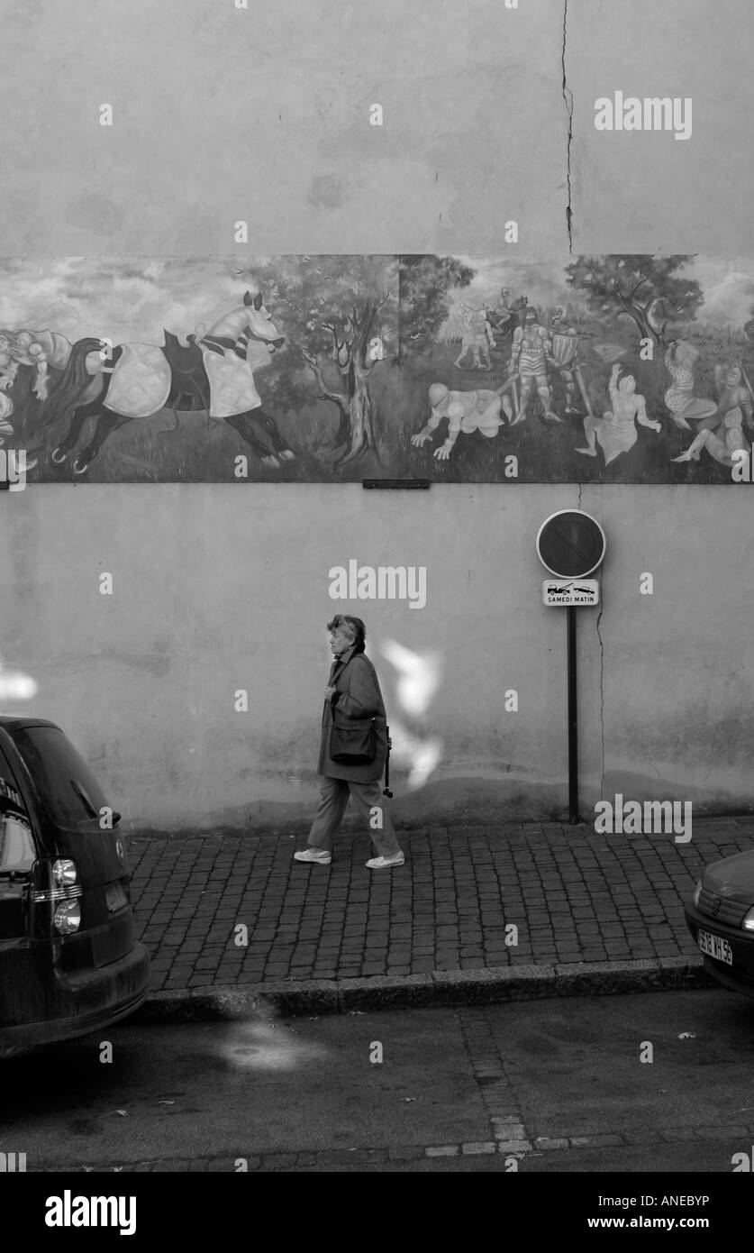 Woman walking past a mural depicting a medieval battle in a French ...