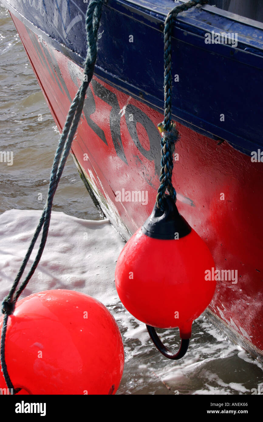 Orange red buoys hanging from bow of small boat Stock Photo - Alamy