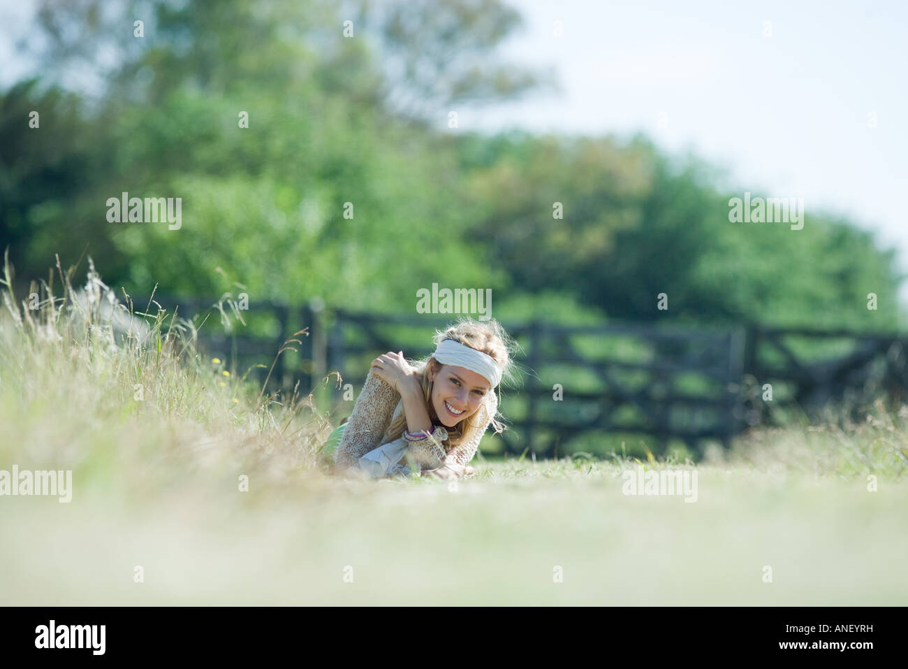 Young woman lying in field, smiling at camera Stock Photo - Alamy