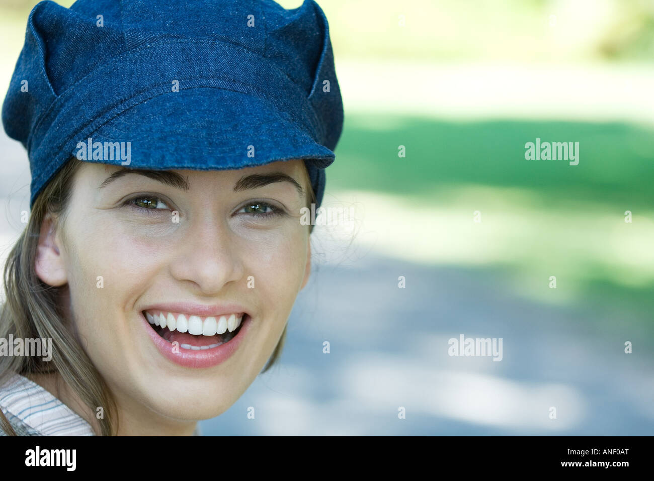 Young woman wearing cap, smiling at camera, portrait Stock Photo - Alamy
