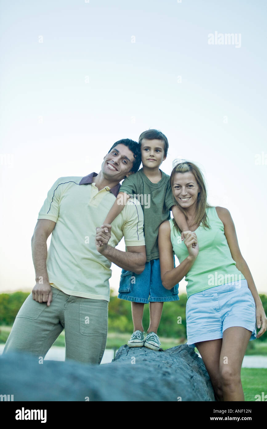 Boy standing on log, between parents Stock Photo - Alamy