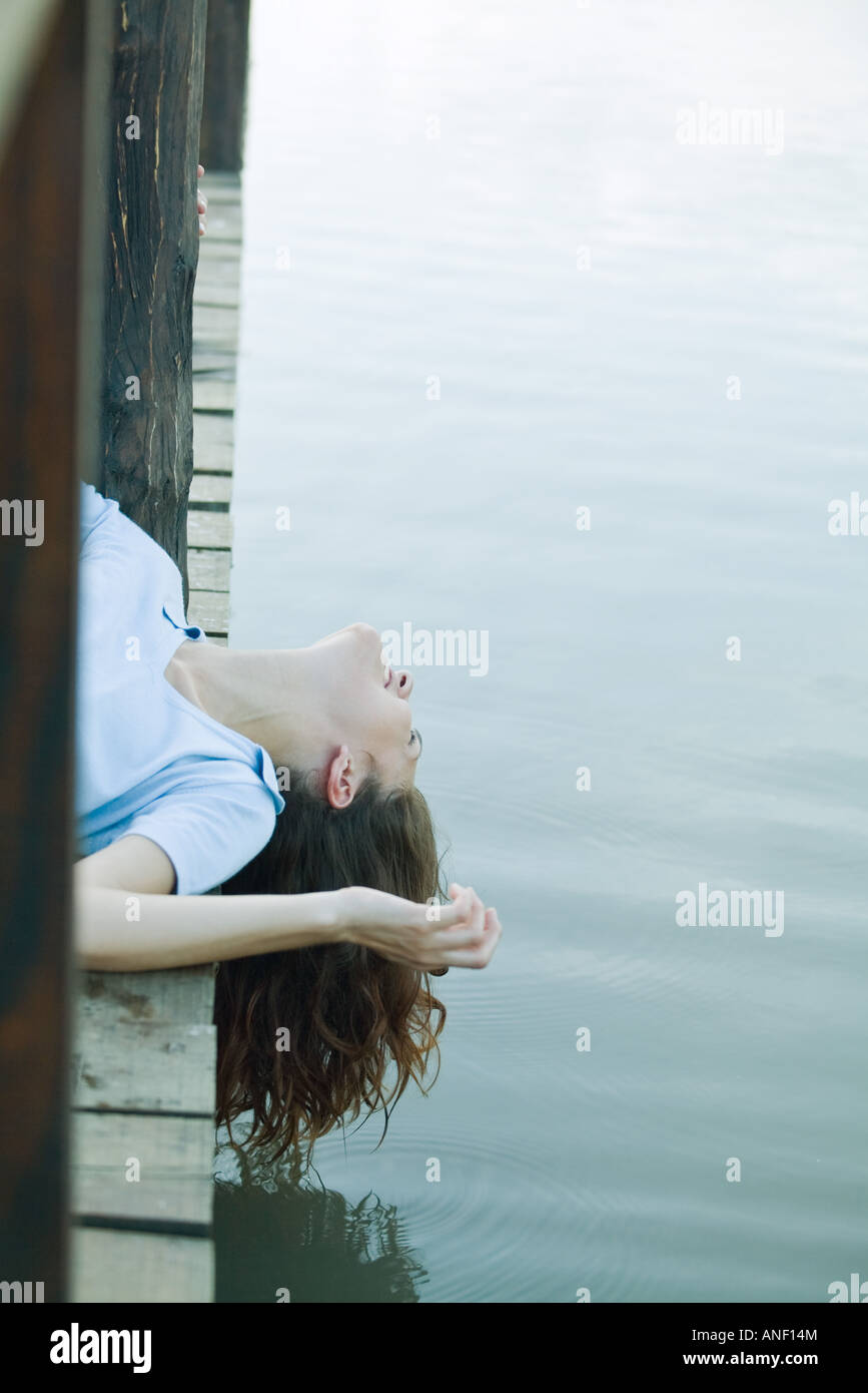 Woman lying on dock, dangling head off edge Stock Photo - Alamy