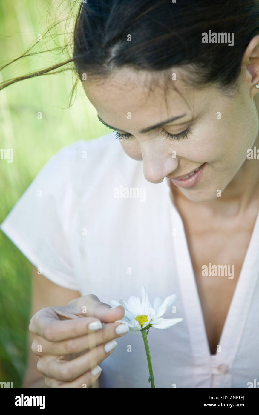 Woman holding flower, looking down, smiling, close-up Stock Photo - Alamy