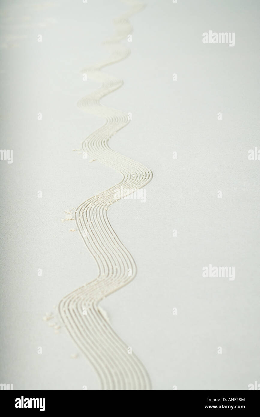 Squiggle pattern track traced into sand Stock Photo - Alamy