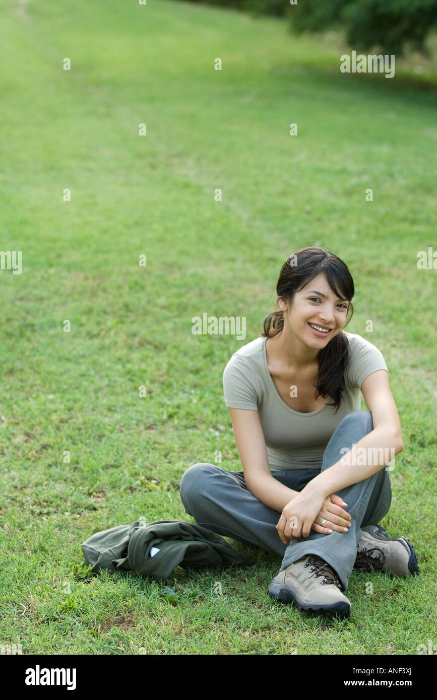 Young woman sitting on grass, smiling at camera Stock Photo - Alamy