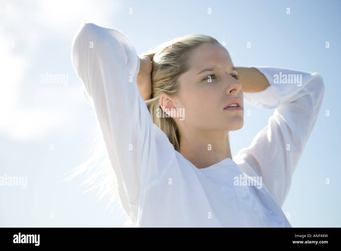 Young woman standing in wind, pushing hair back Stock Photo - Alamy