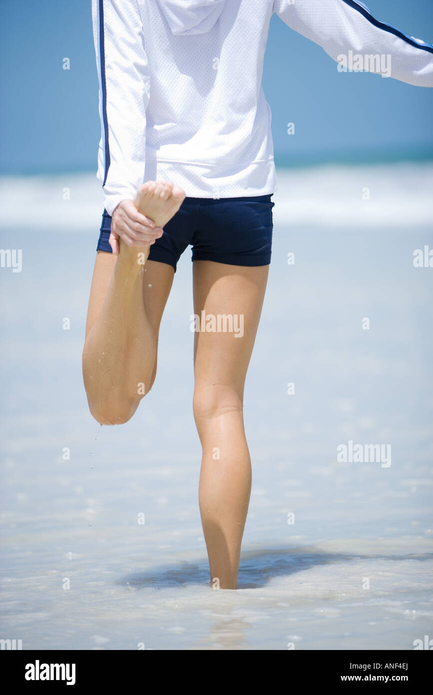Young woman on beach, stretching Stock Photo - Alamy