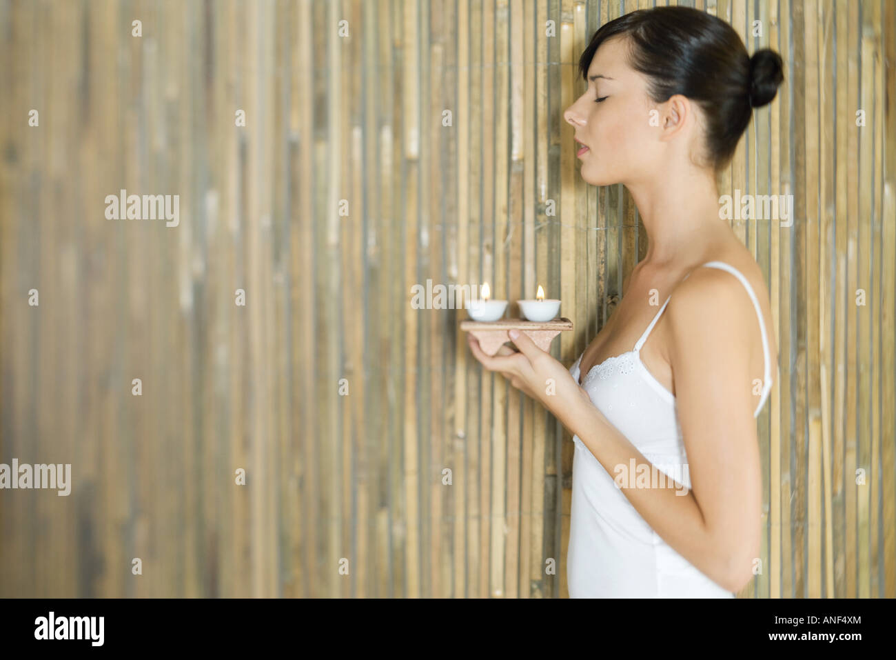 Young woman holding tray of candles, side view Stock Photo - Alamy