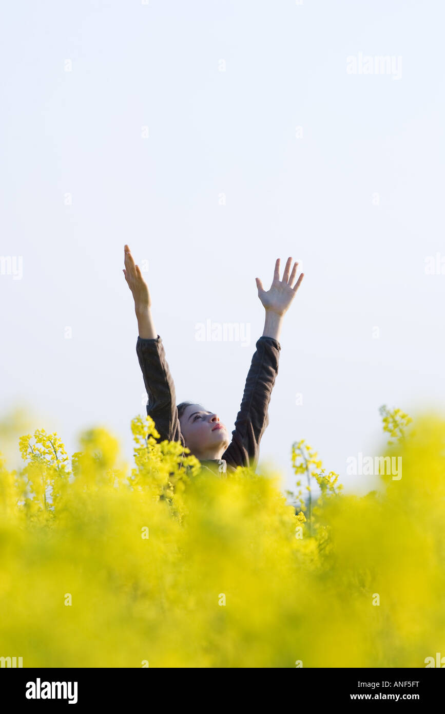 Girl standing in field with arms raised, looking up at sky Stock Photo ...