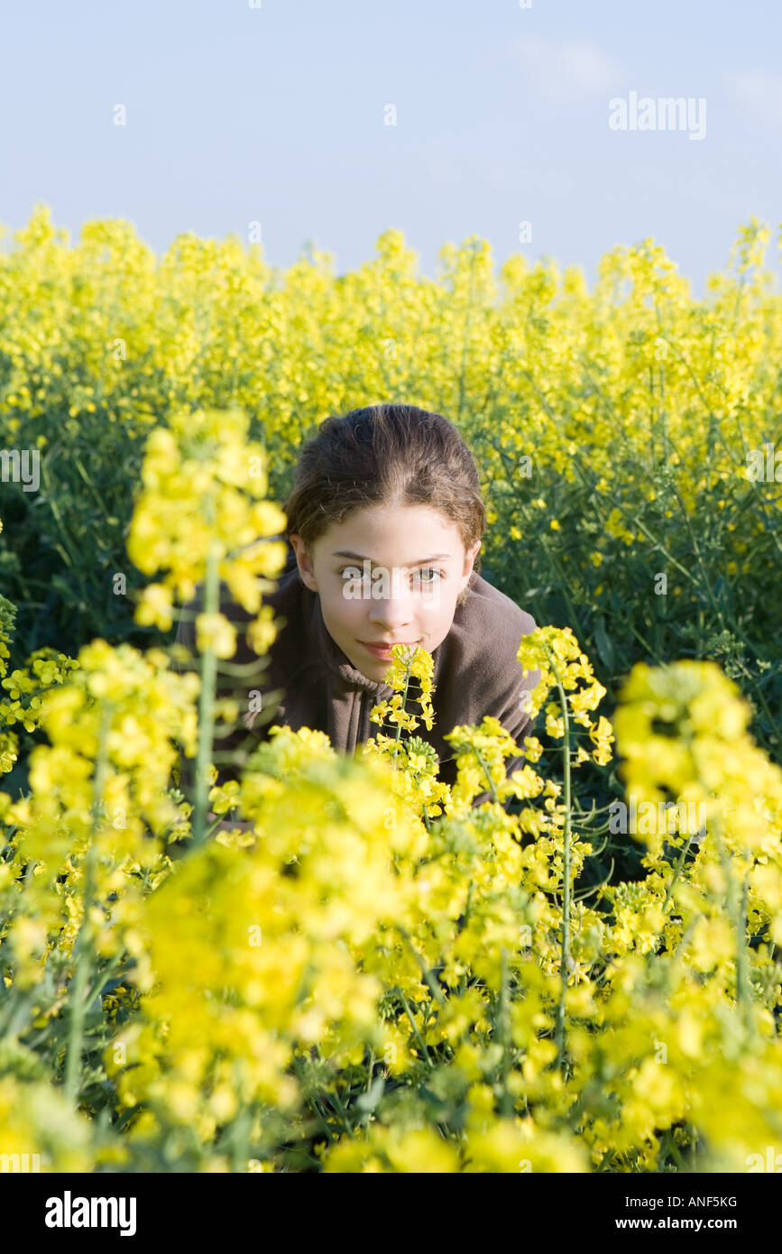 Girl leaning forward in field of canola, smiling at cameras Stock Photo ...