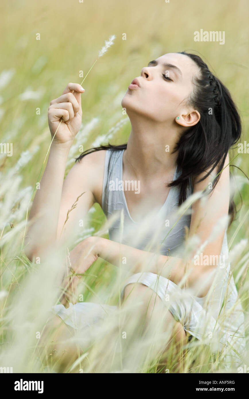 Teen girl sitting in field, holding sprig of long grass Stock Photo - Alamy