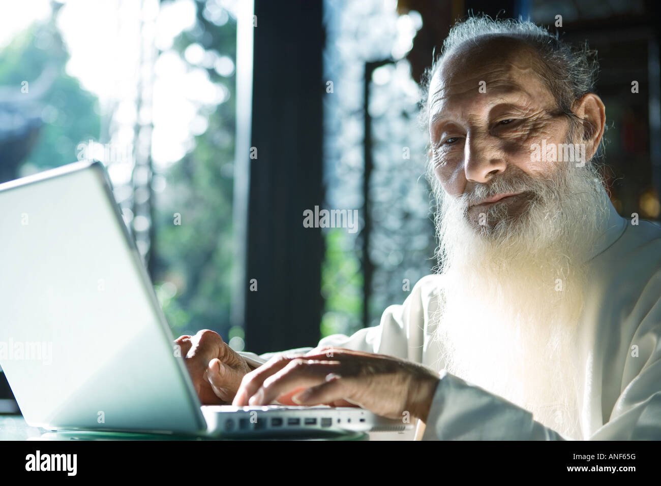 Elderly man in traditional Chinese clothing using laptop computer Stock ...