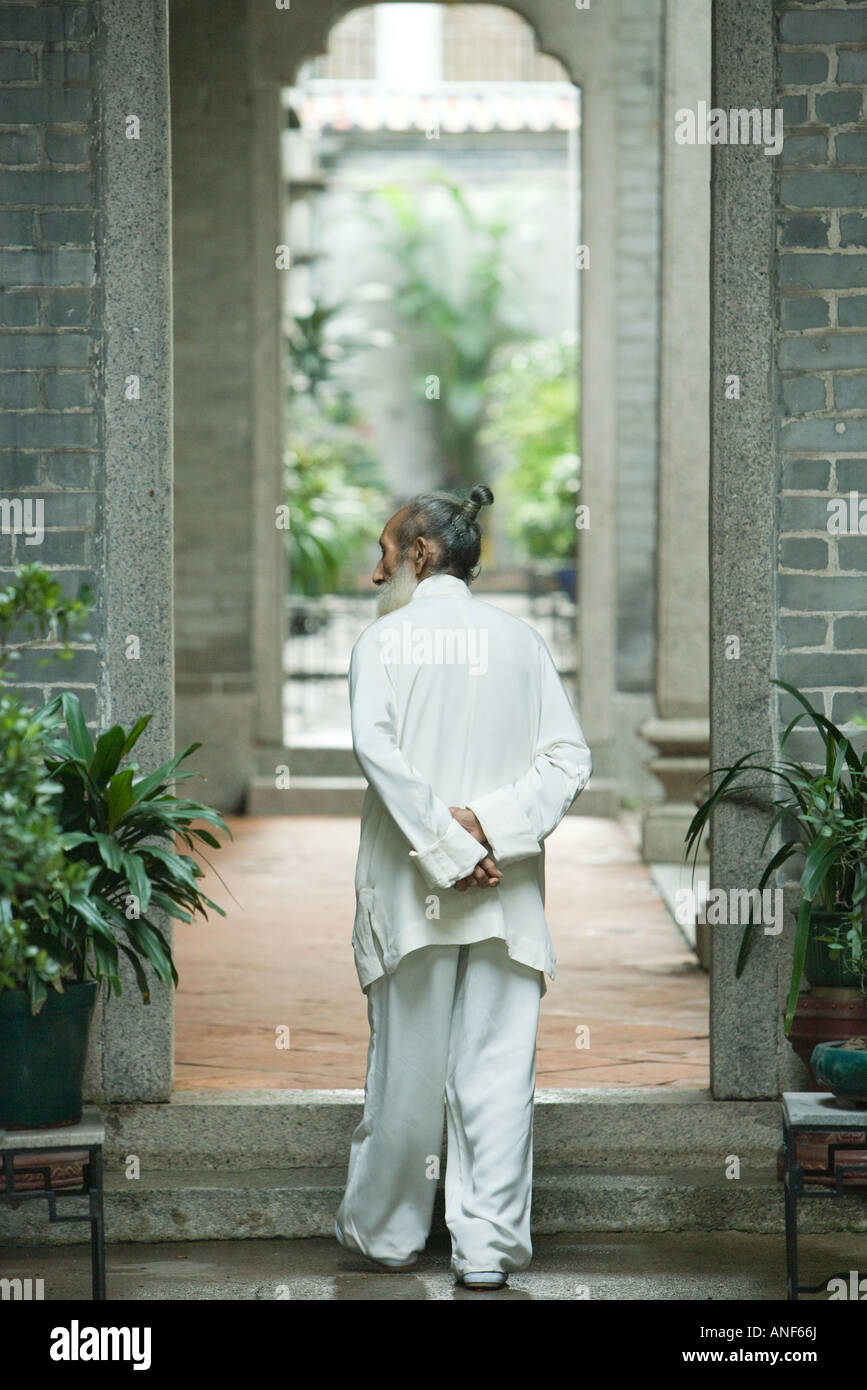 Elderly man in traditional Chinese clothing, walking through archway ...