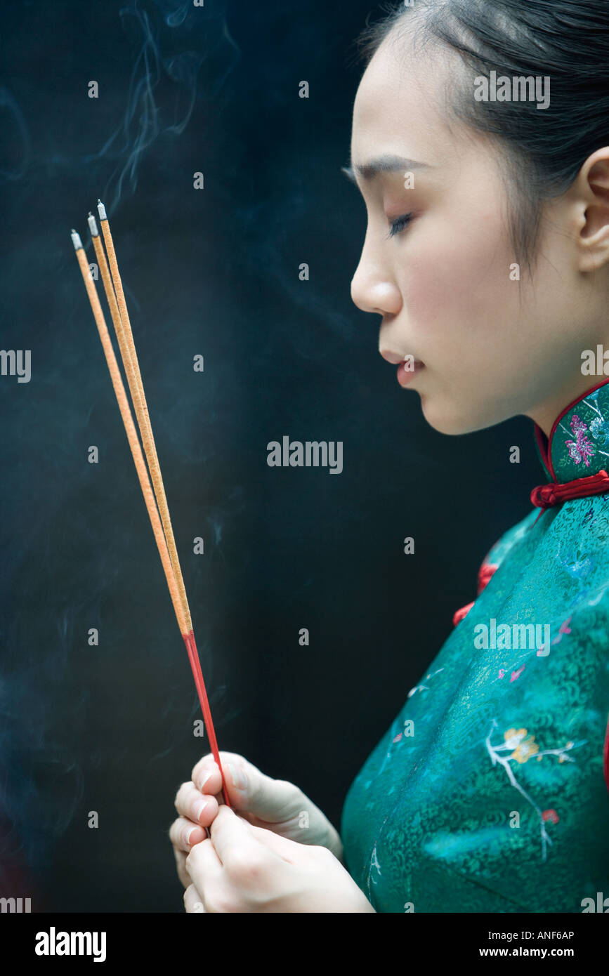 Young woman dressed in traditional Chinese clothing holding sticks of ...