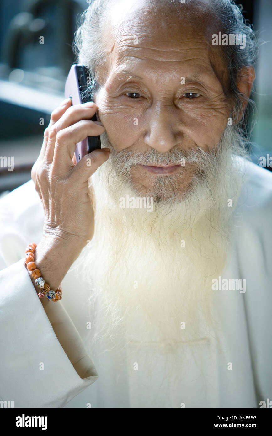 Elderly man in traditional Chinese clothing with long beard, using cell ...