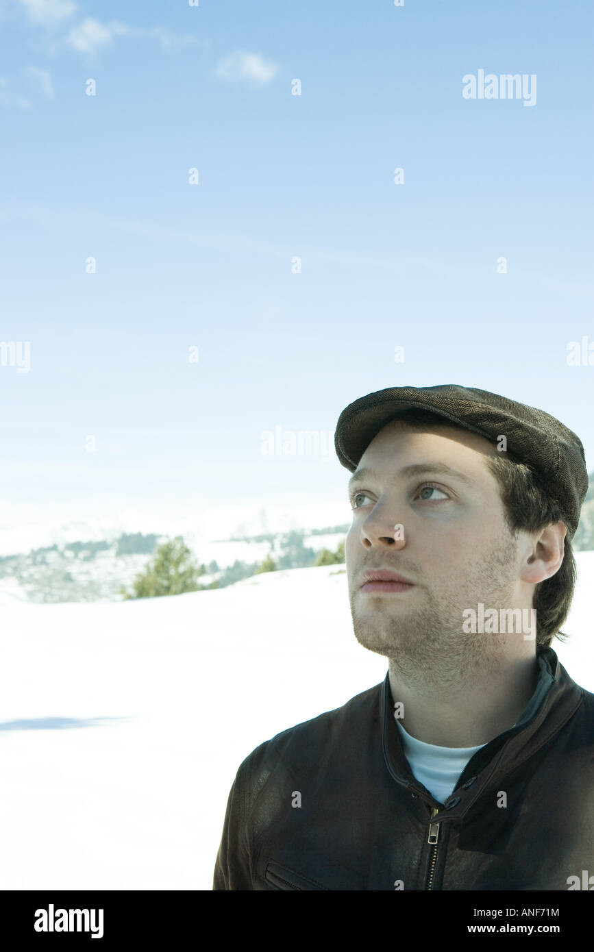 Young man wearing hat in snowy landscape, looking up Stock Photo - Alamy