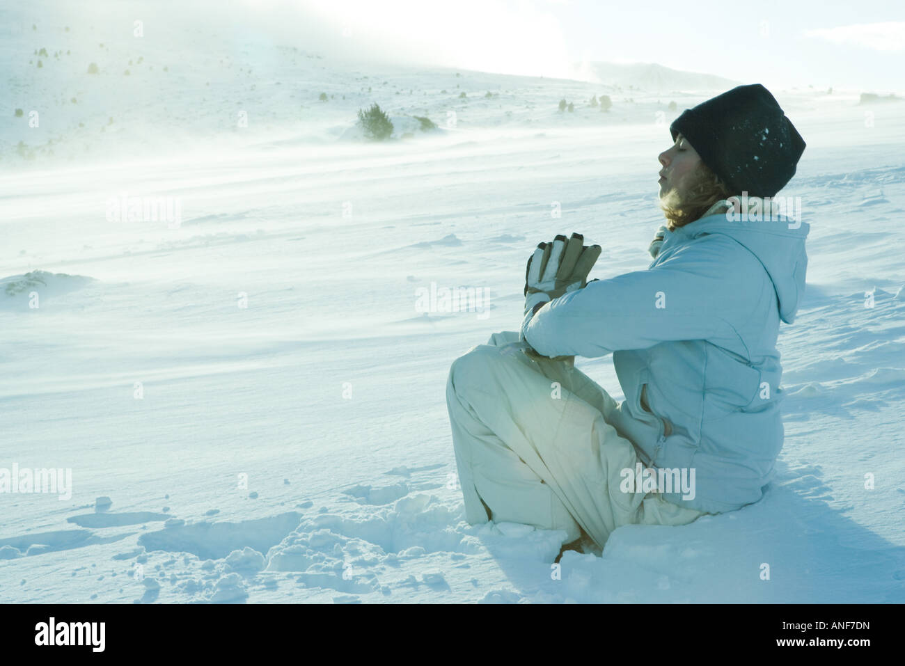 Teen girl sitting on snow in prayer position Stock Photo - Alamy
