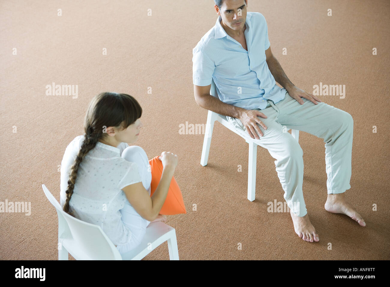 Man and woman sitting in chairs, looking away, high angle view Stock ...