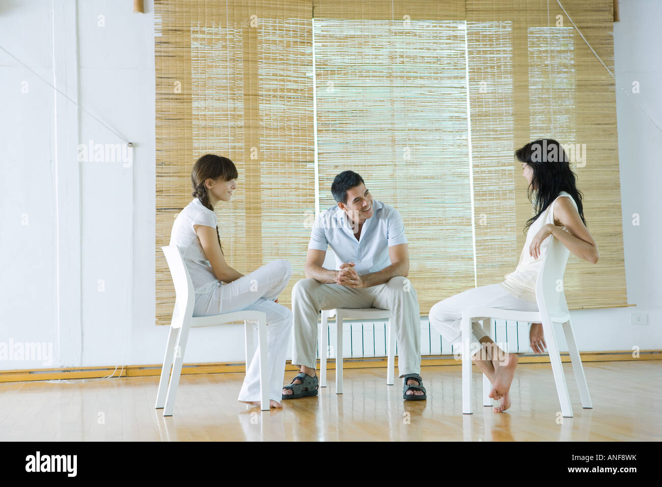 Three adults sitting in chairs, having therapy session, smiling Stock ...