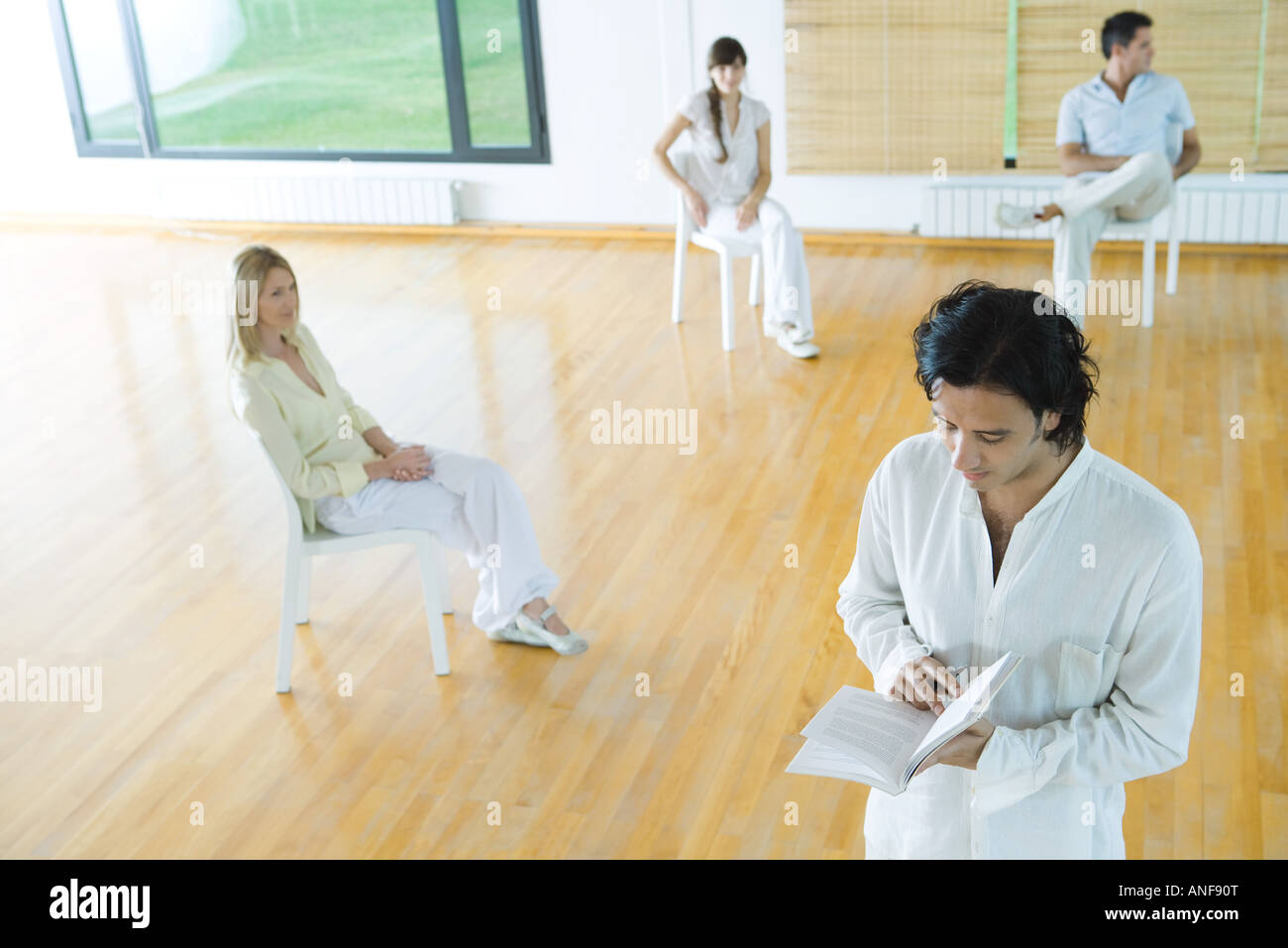 Man standing reading book during group therapy session Stock Photo - Alamy