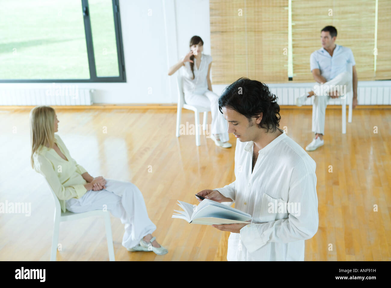 Man standing reading book during group therapy session Stock Photo - Alamy