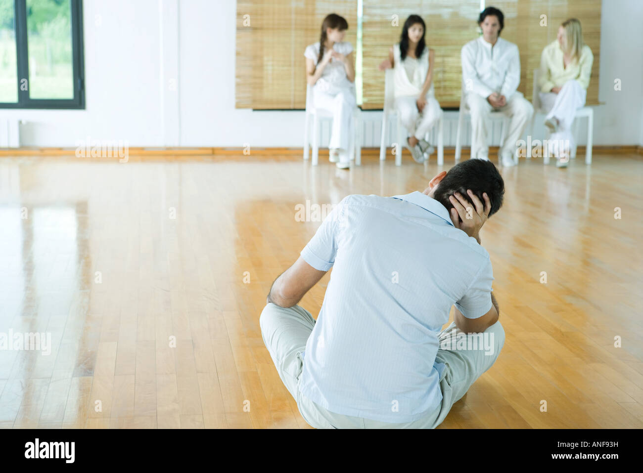 Man sitting on floor, facing group sitting in chairs Stock Photo - Alamy