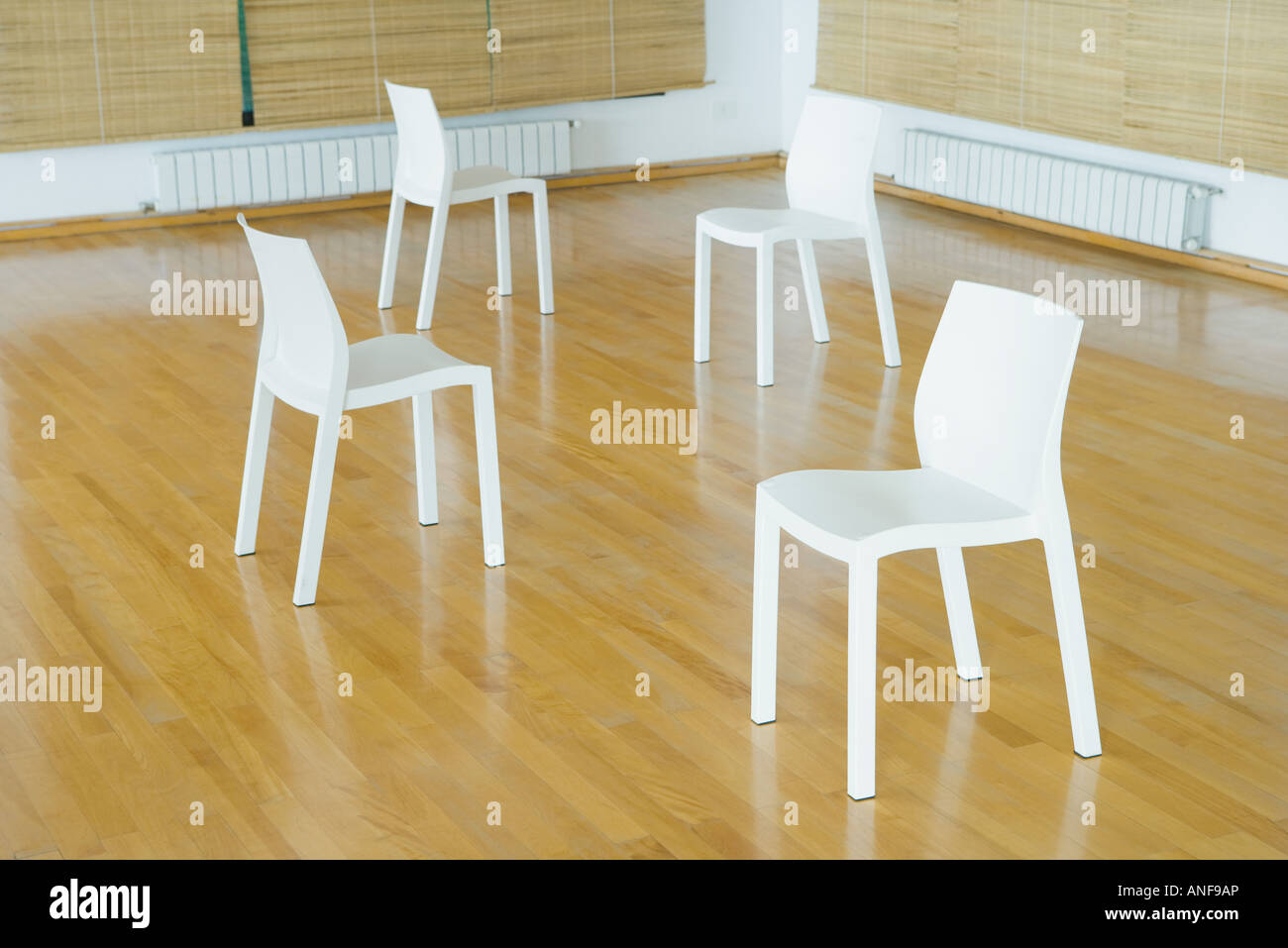Four empty chairs on hardwood floor Stock Photo - Alamy