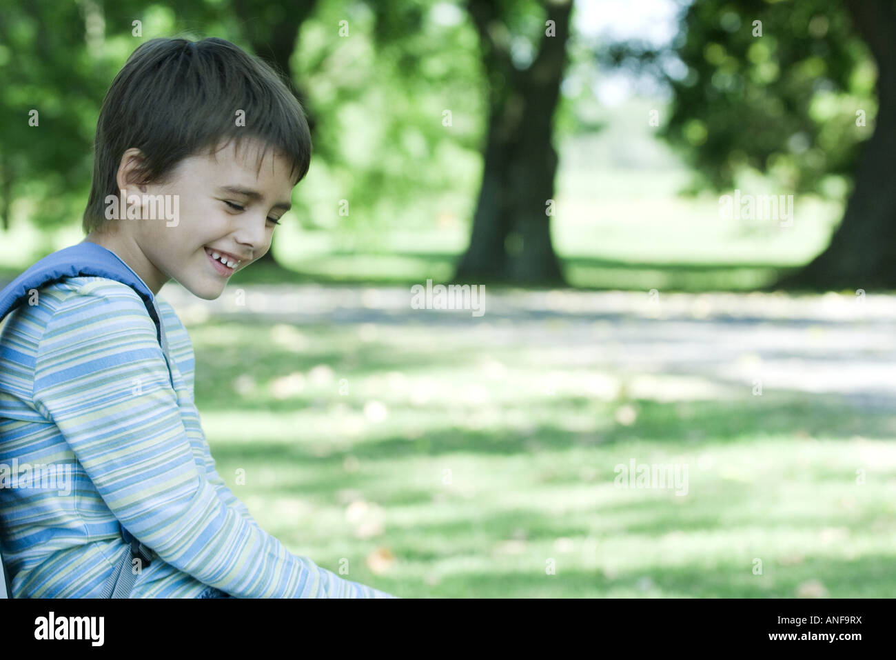 Boy sitting in park, laughing, side view Stock Photo - Alamy