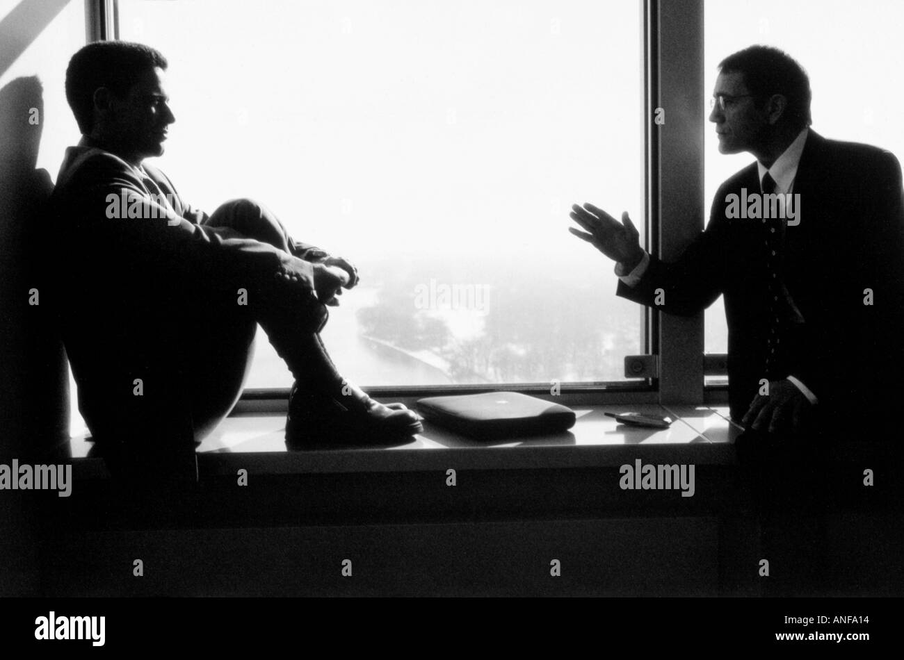 two businessmen sitting on the sill in a modern office Stock Photo - Alamy