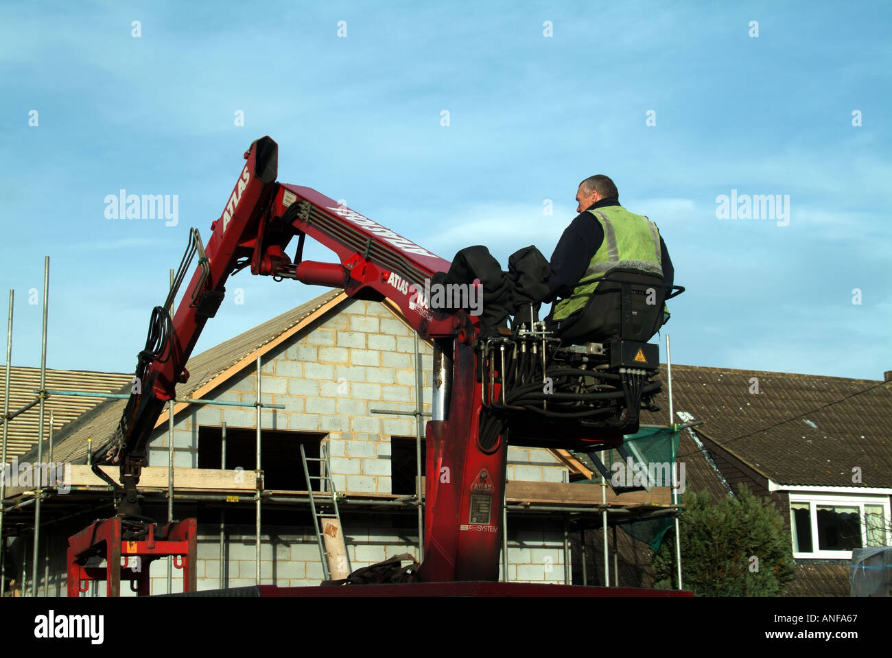 Truck driver working a lorry mounted crane unloading building materials ...