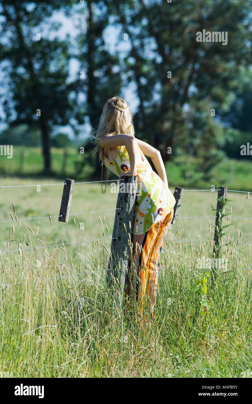 Young woman leaning over rural fence, rear view Stock Photo - Alamy