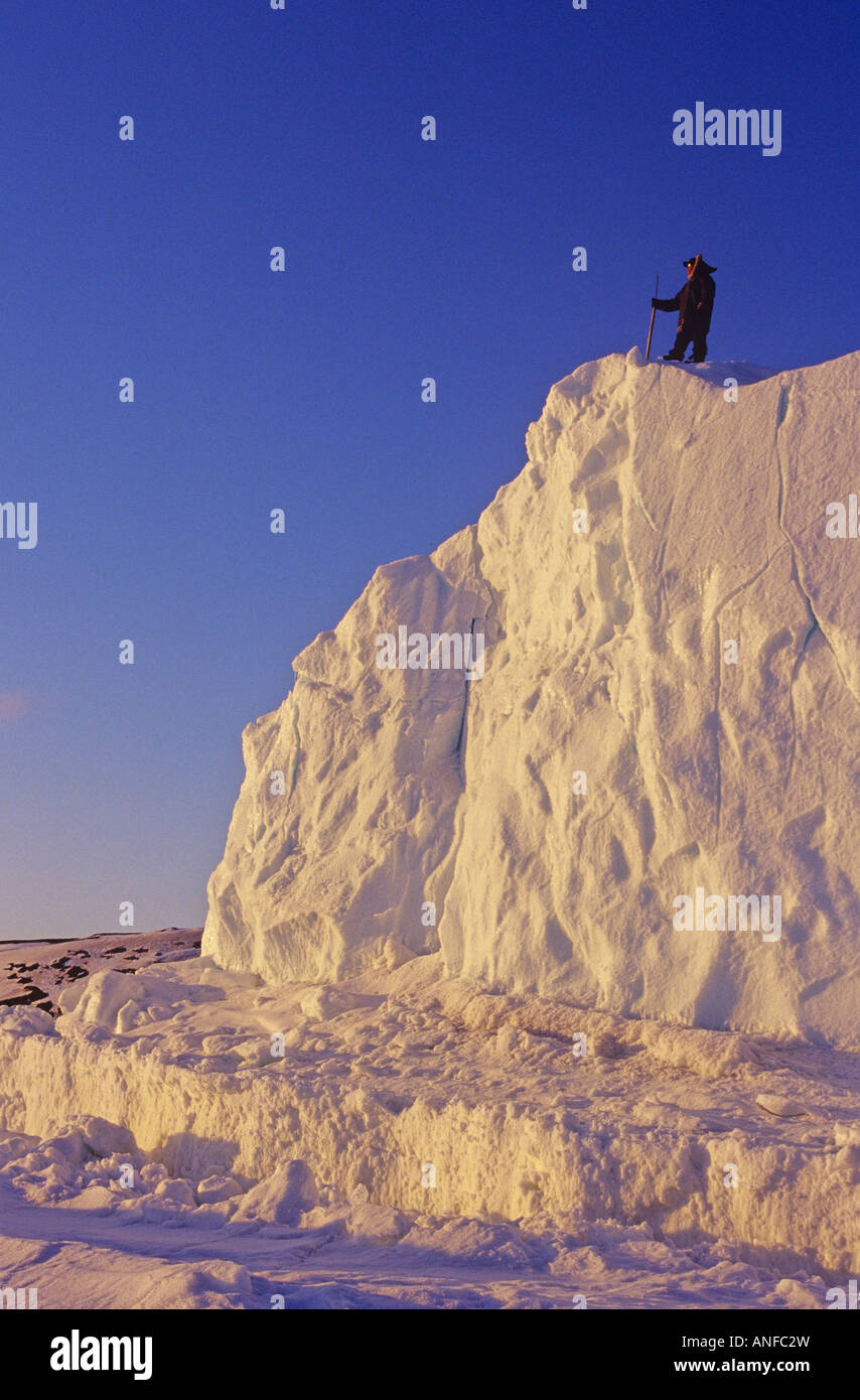 Inuit hunter watches sunset from iceberg frozen in sea ice, Kimmirut ...