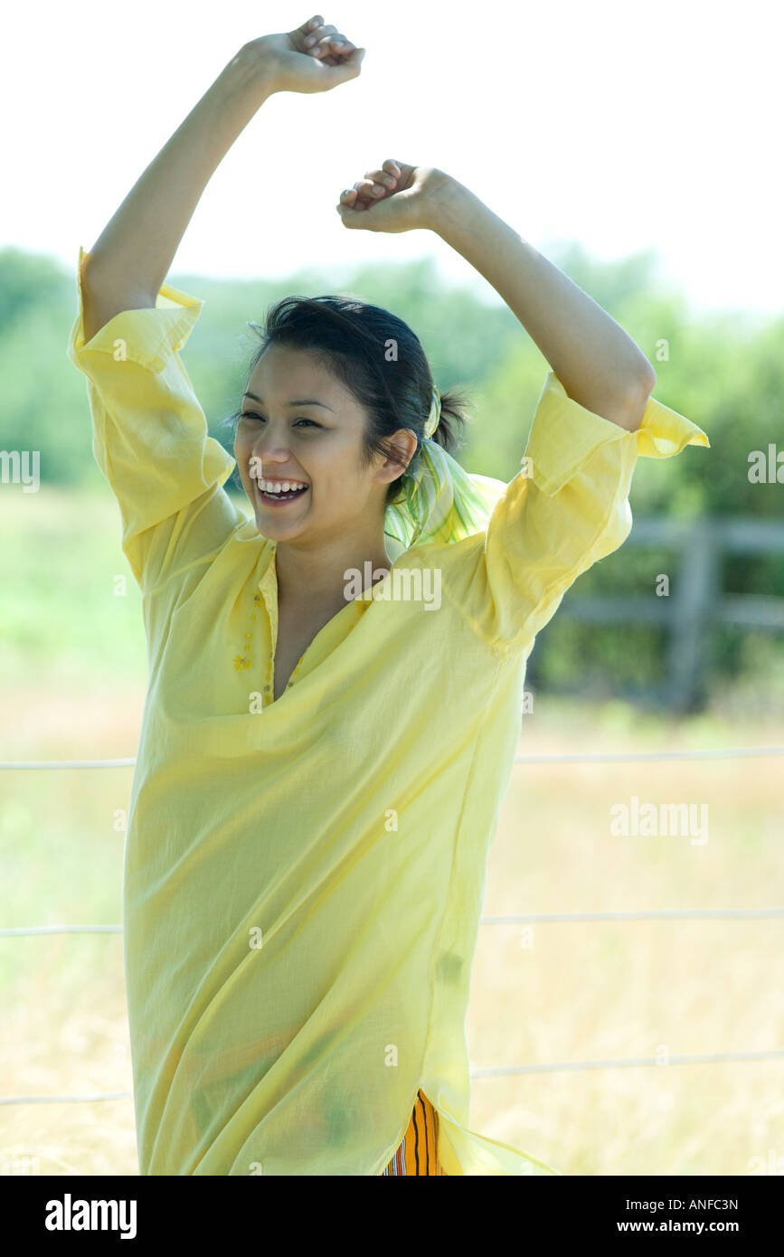 Young woman standing with arms raised, smiling Stock Photo - Alamy