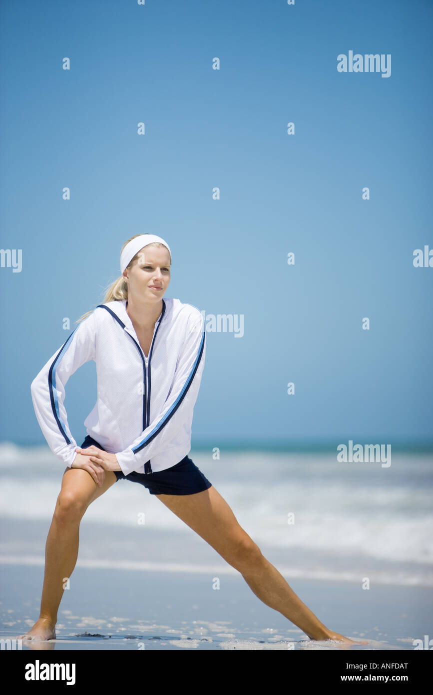 Young woman in active wear, stretching on beach Stock Photo - Alamy