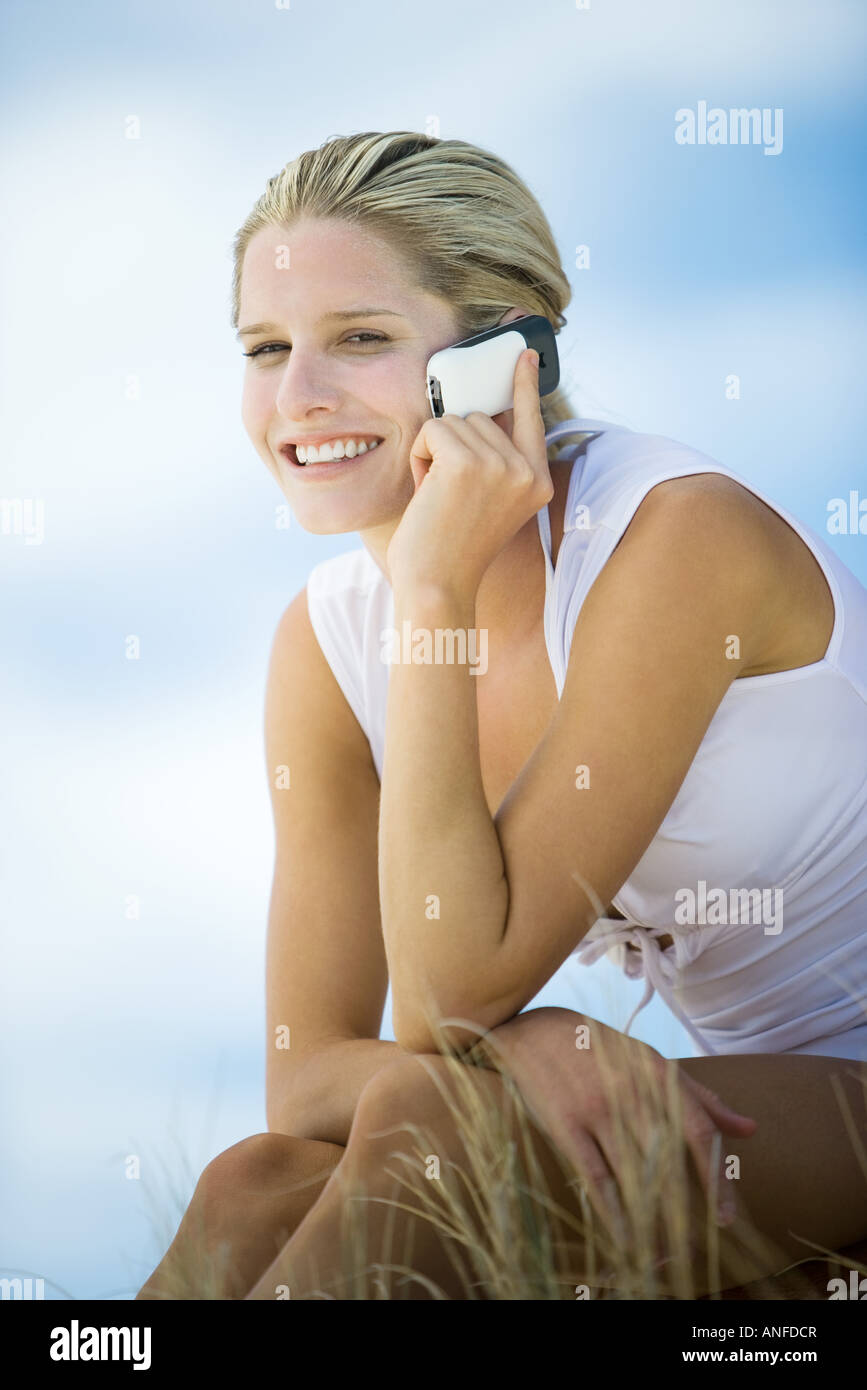 Young woman using cell phone outdoors, smiling Stock Photo - Alamy