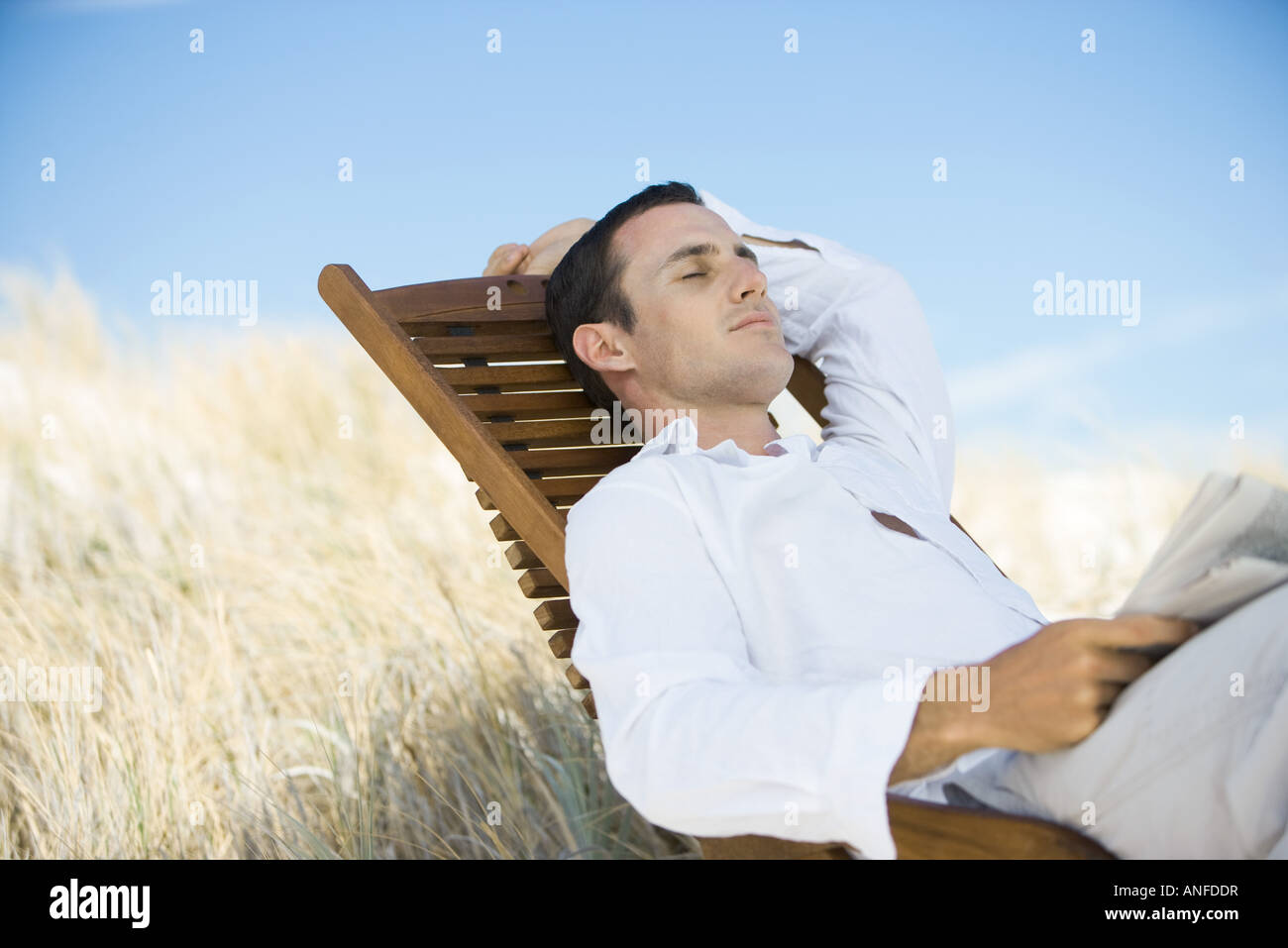 Young man sitting in deck chair, napping Stock Photo - Alamy