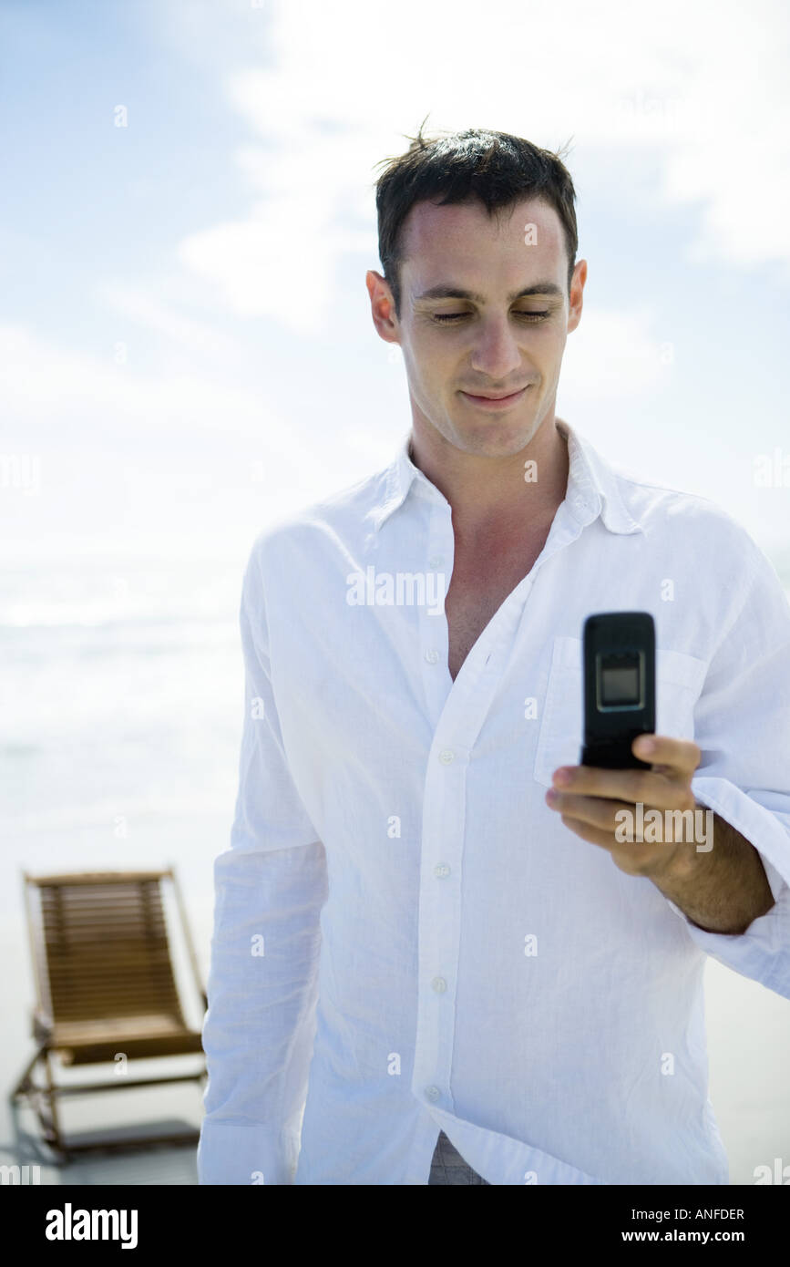 Young man using cell phone on beach Stock Photo - Alamy