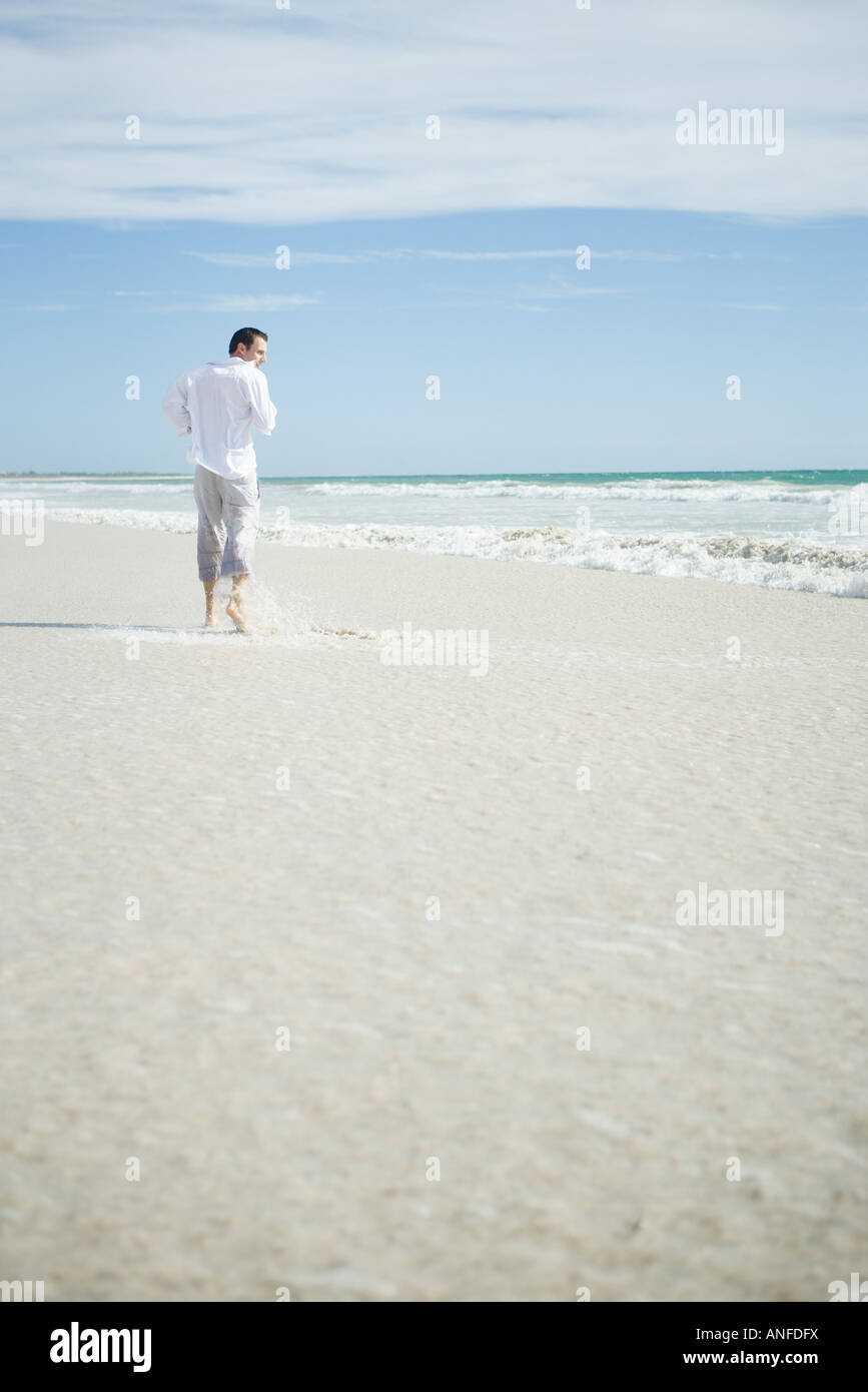Young man running through surf on beach, rear view Stock Photo - Alamy