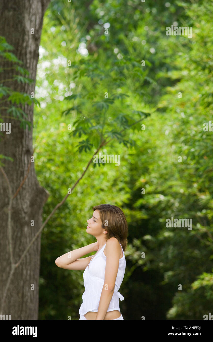 Young woman standing beside tree, smiling, side view Stock Photo - Alamy
