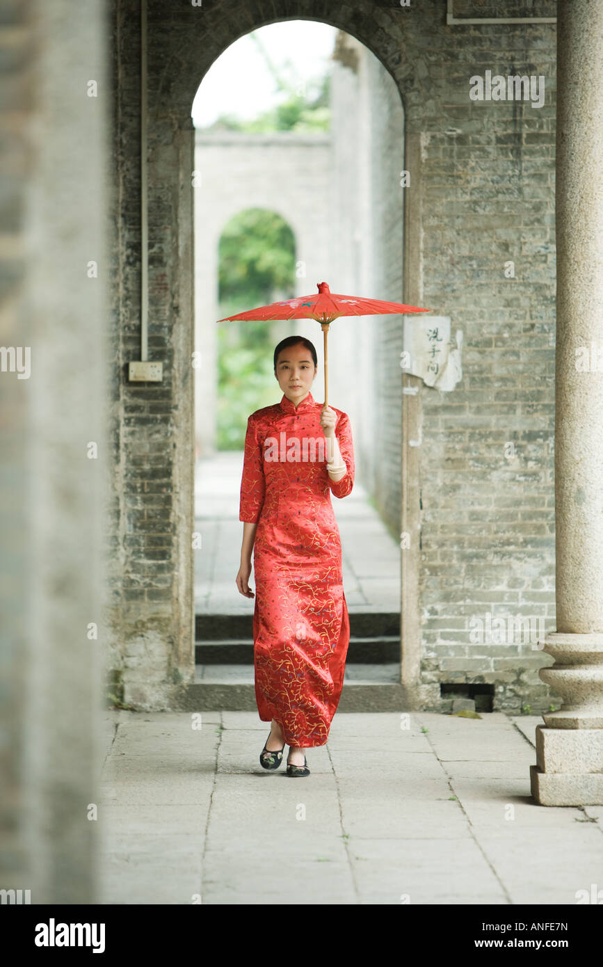 Young woman wearing traditional Chinese clothing, walking with parasol ...