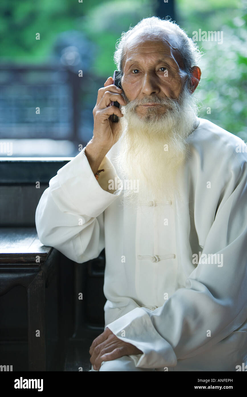 Elderly man wearing traditional Chinese clothing, using cell phone ...