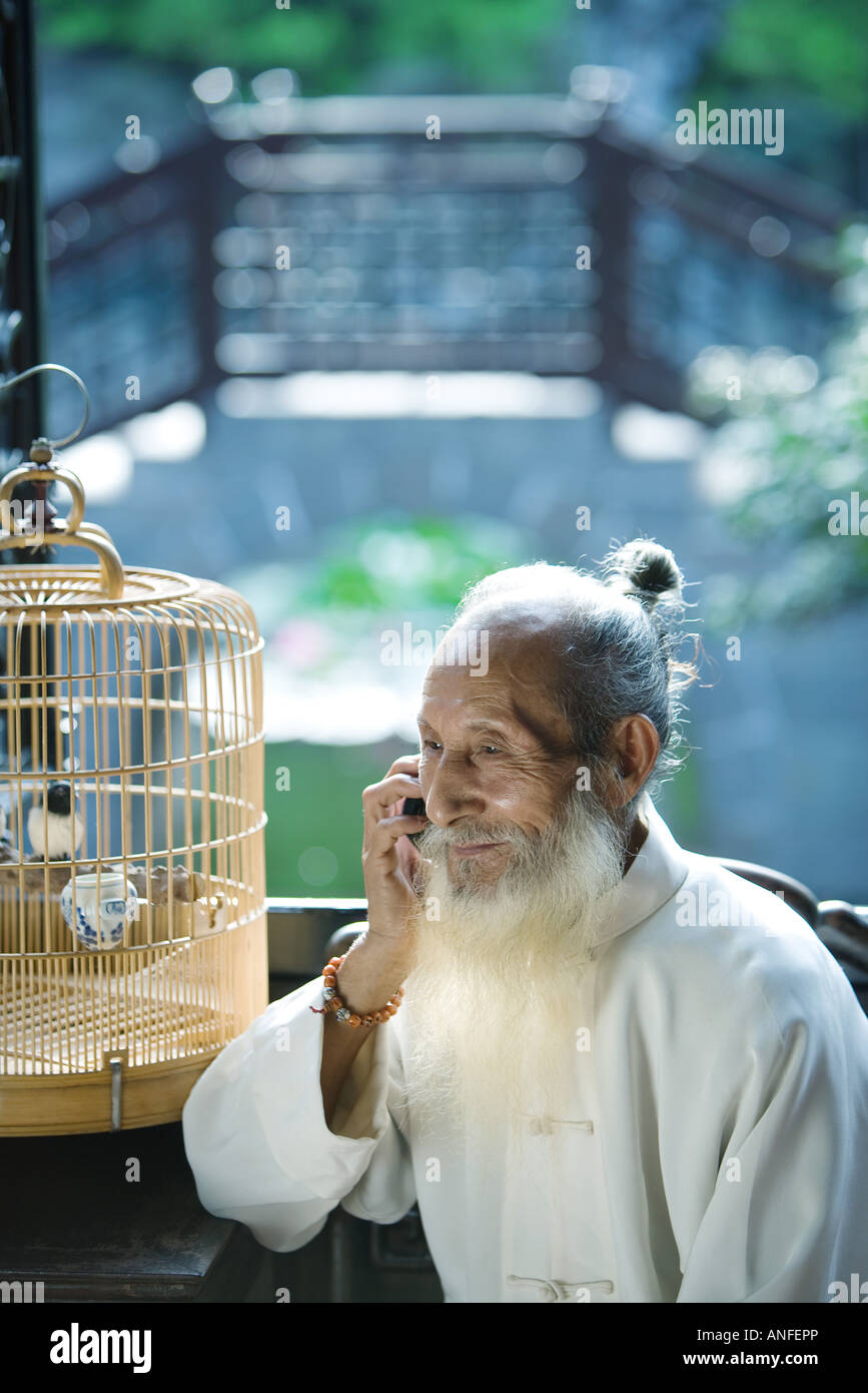 Elderly man wearing traditional Chinese clothing, using cell phone ...