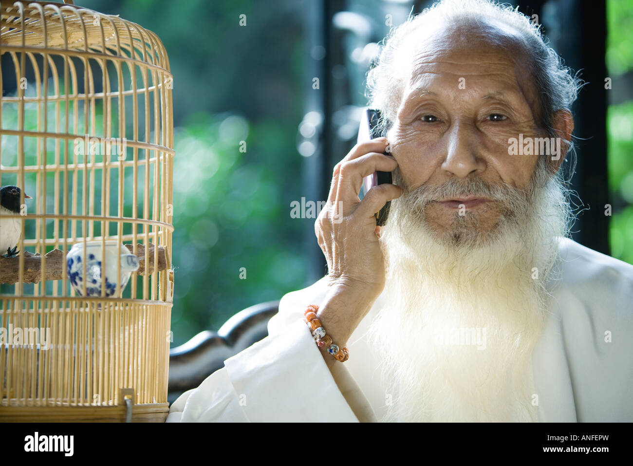 Elderly man wearing traditional Chinese clothing, using cell phone ...