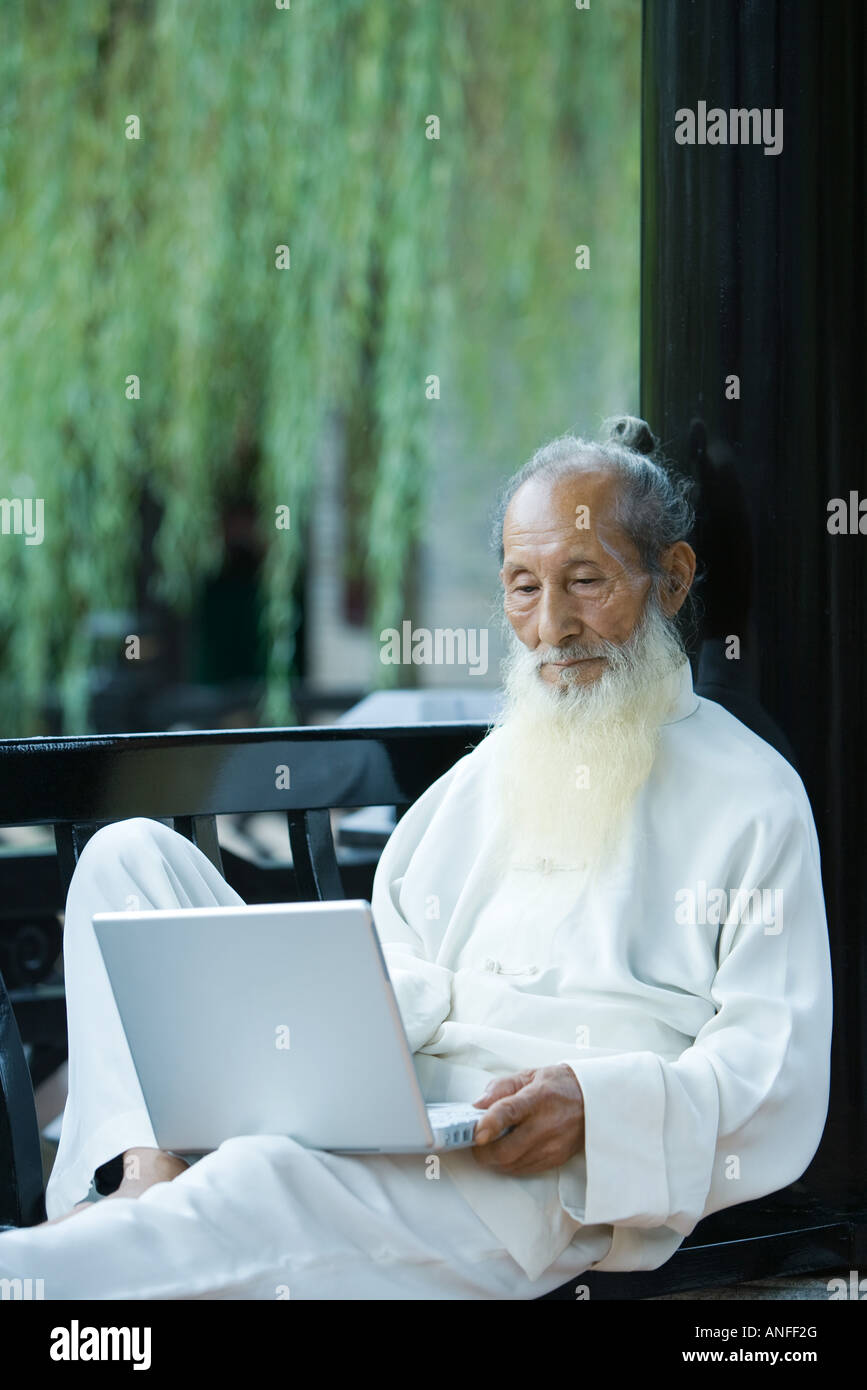 Elderly man wearing traditional Chinese clothing, using laptop Stock ...