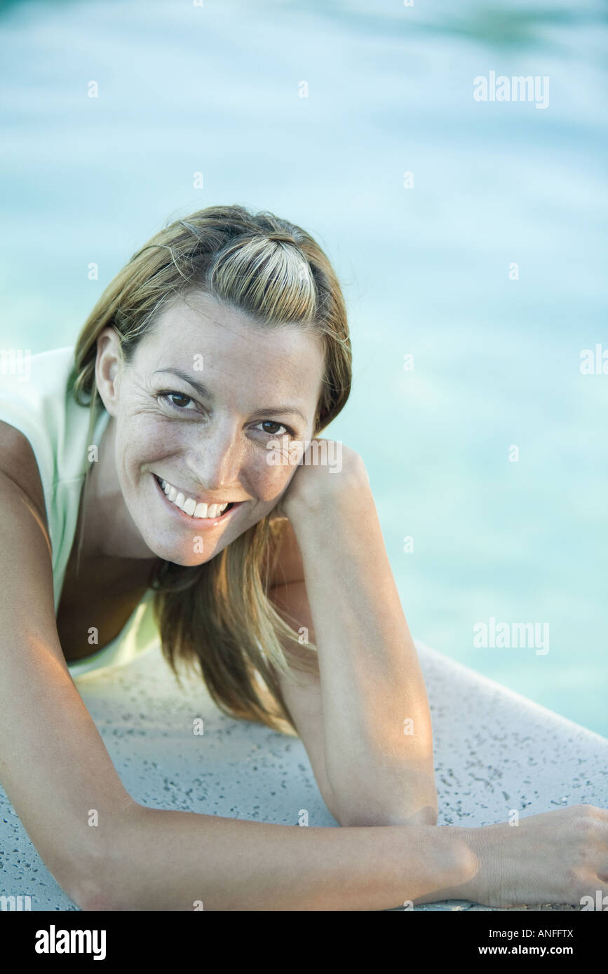 Woman lying by edge of pool, smiling at camera Stock Photo - Alamy
