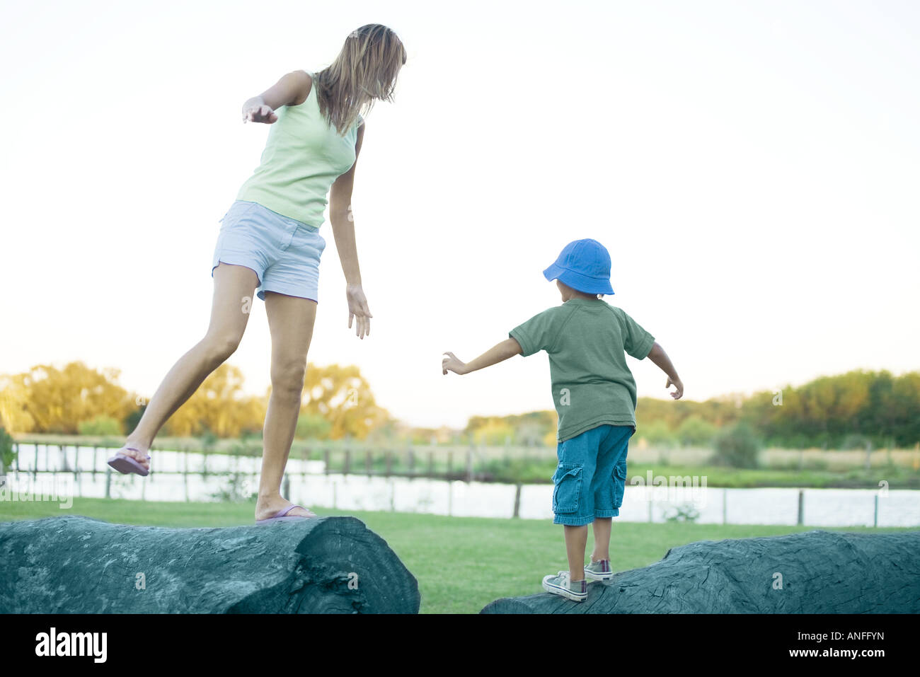 Boy and mother balancing on logs Stock Photo - Alamy