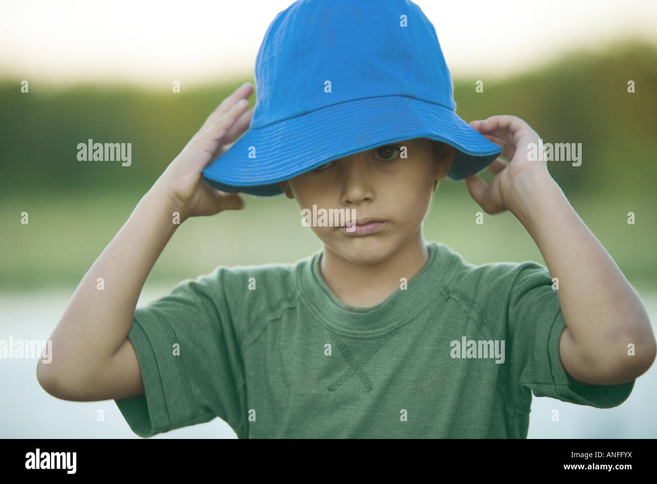 Boy putting on hat, head and shoulders Stock Photo - Alamy