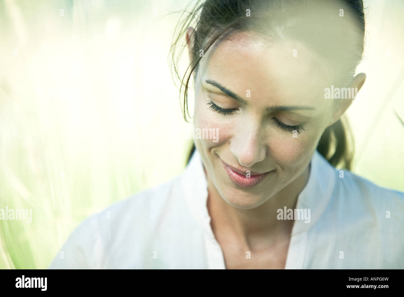 Woman in field, looking down, portrait Stock Photo - Alamy