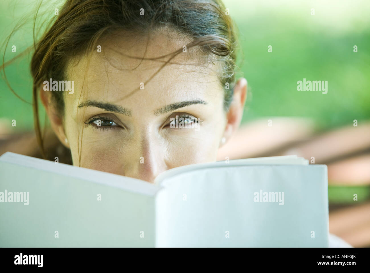 Woman looking over book Stock Photo - Alamy